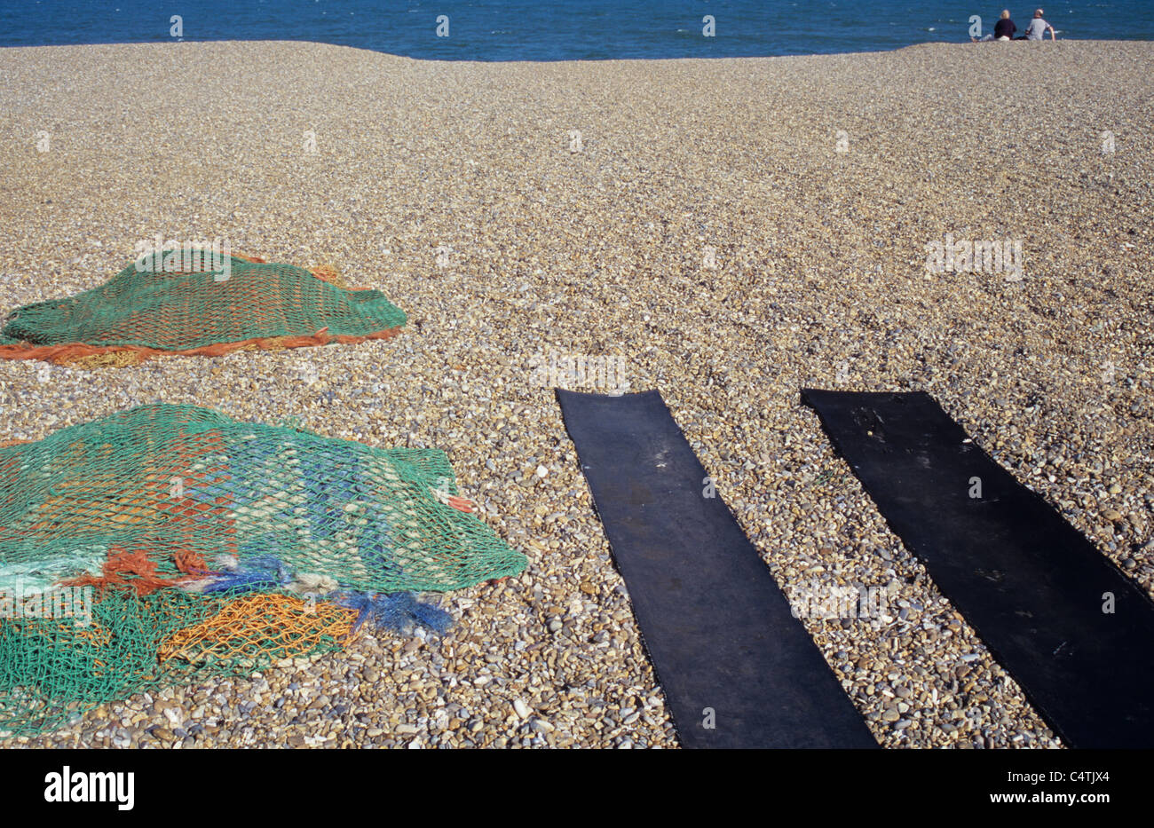 Wide shingle beach with strips of black rubber matting and coloured ...