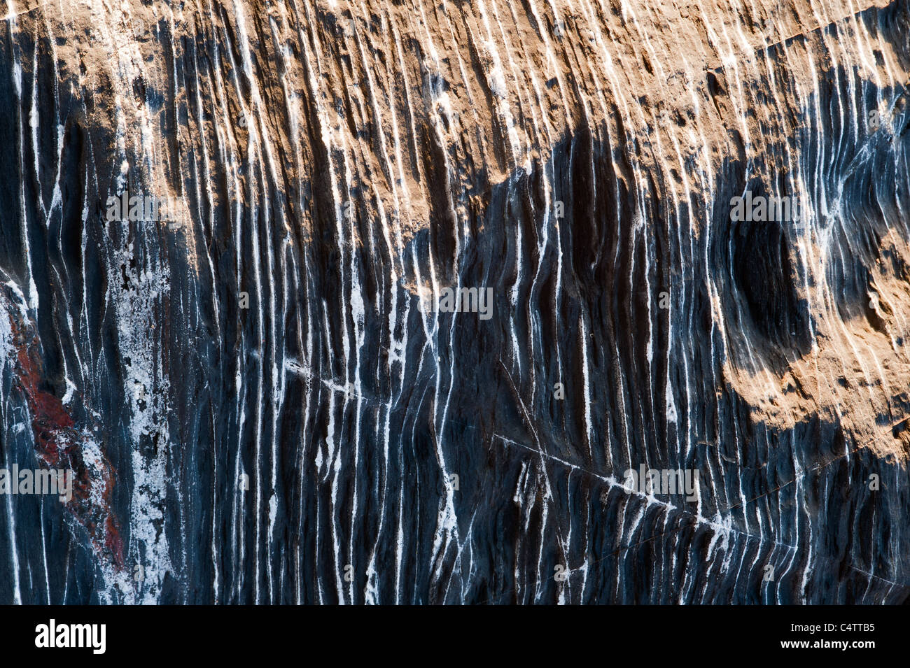 vertical striated rock formation with side lighting Stock Photo - Alamy