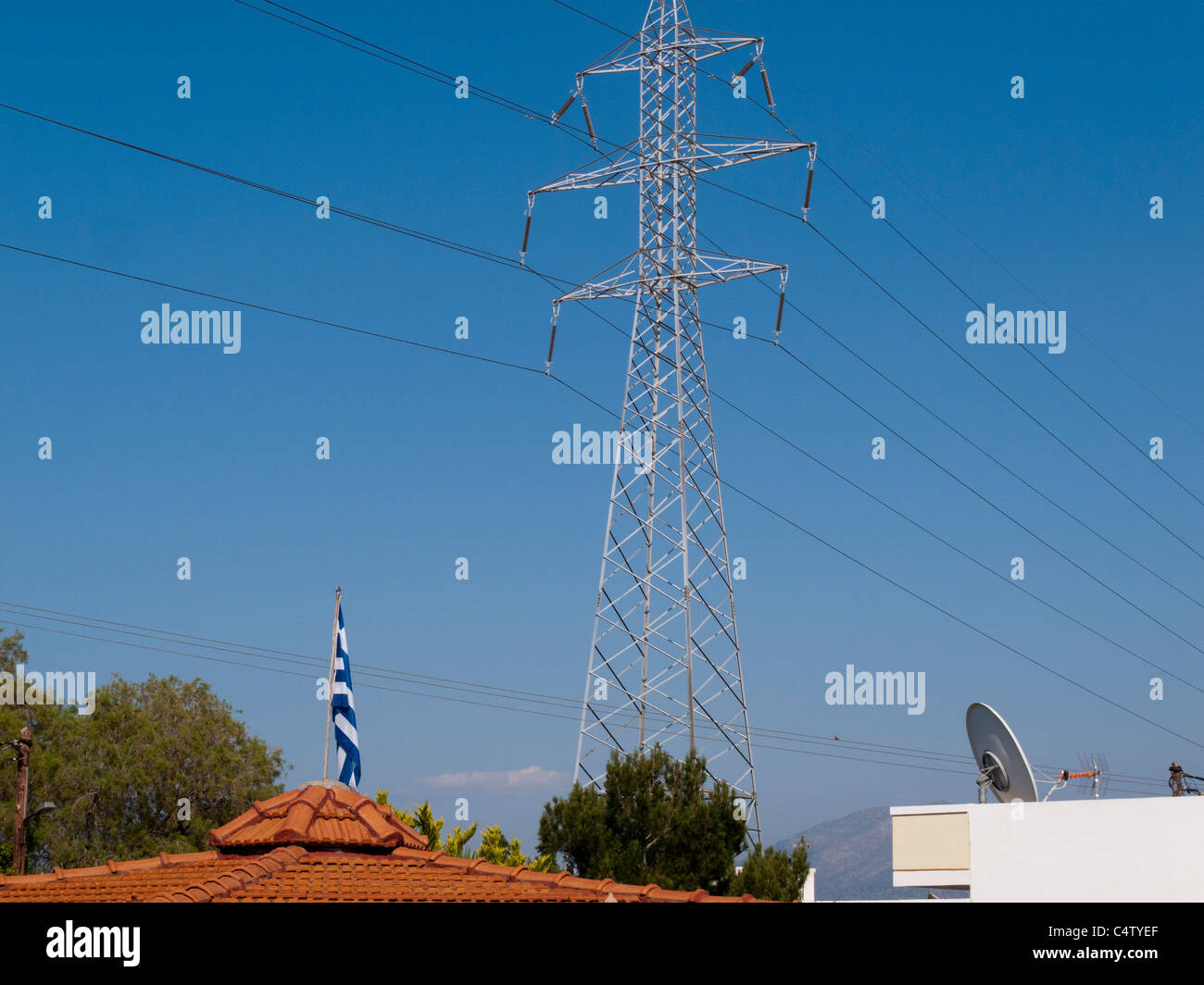 Electric pylon and satellite dishes,over a holiday village in Greece ...