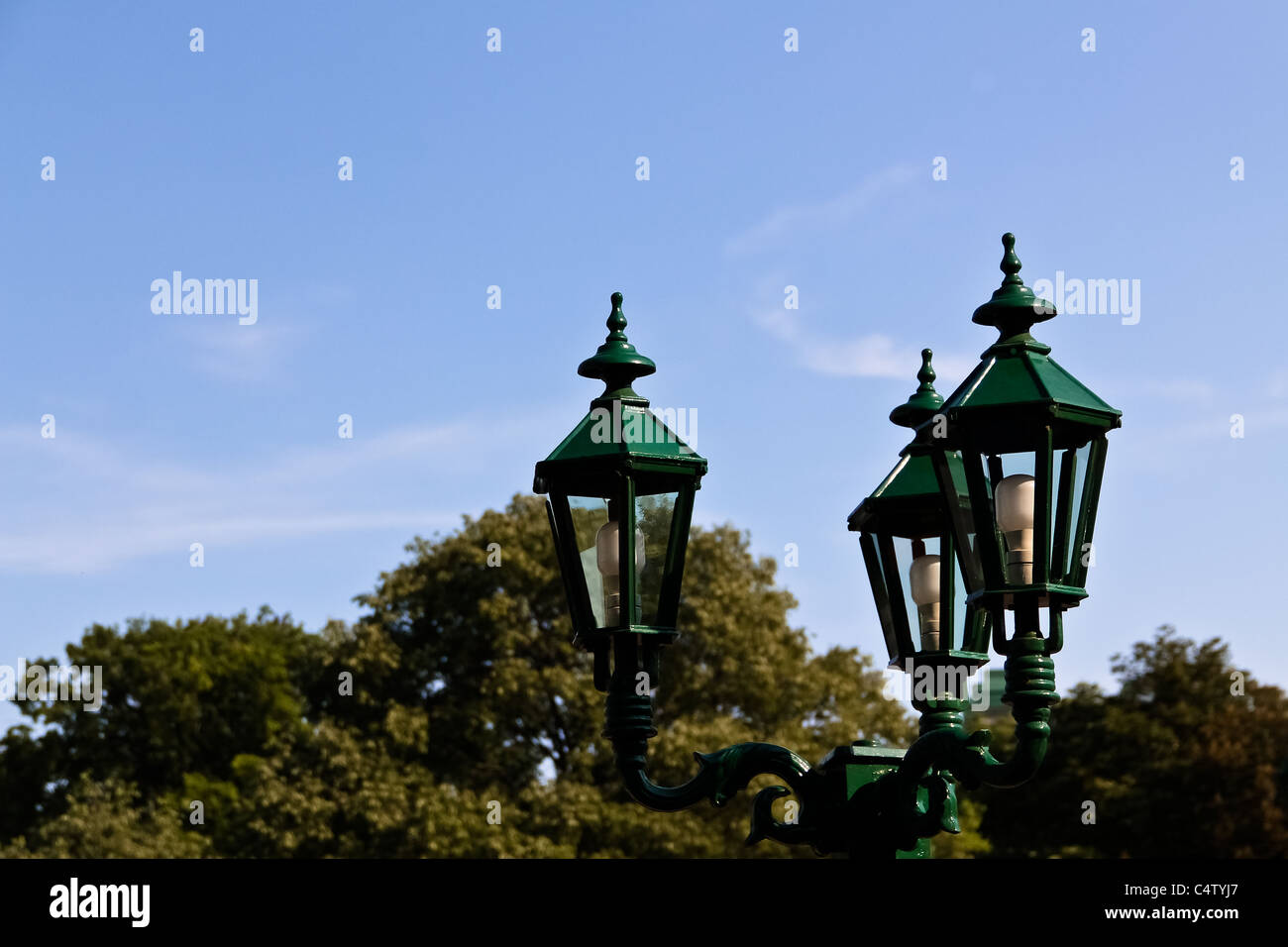 A street lamp with three lights in Vienna in front of trees Stock Photo ...
