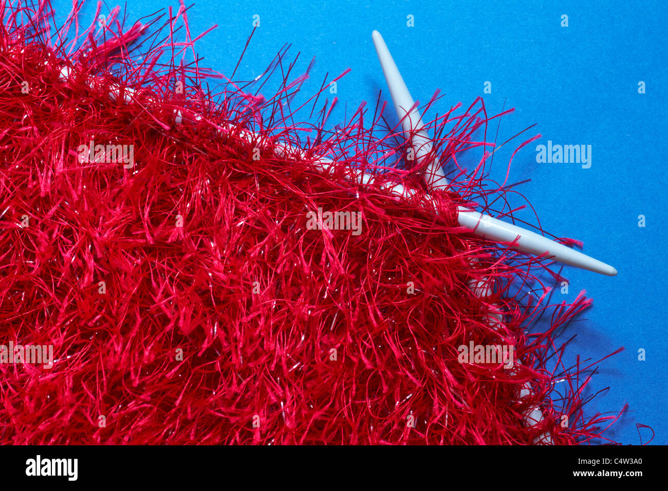 knitting with red fancy wool against blue background Stock Photo - Alamy