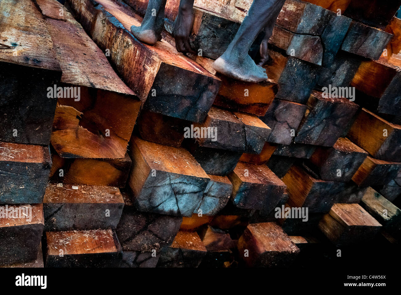 A Colombian worker lifts a heavy timber from a pile at a sawmill in ...