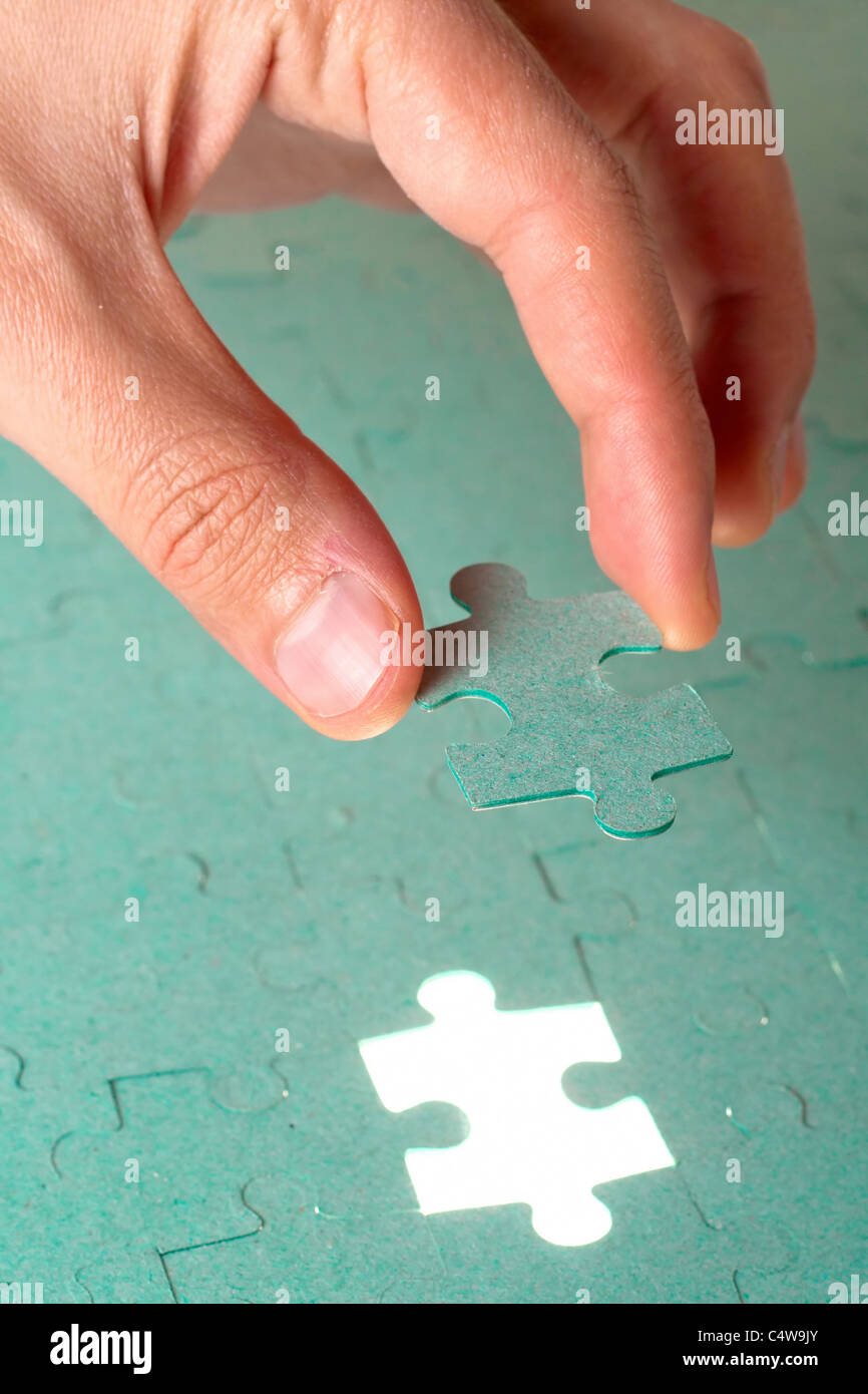 Hand inserting missing piece of green jigsaw puzzle into the hole Stock ...
