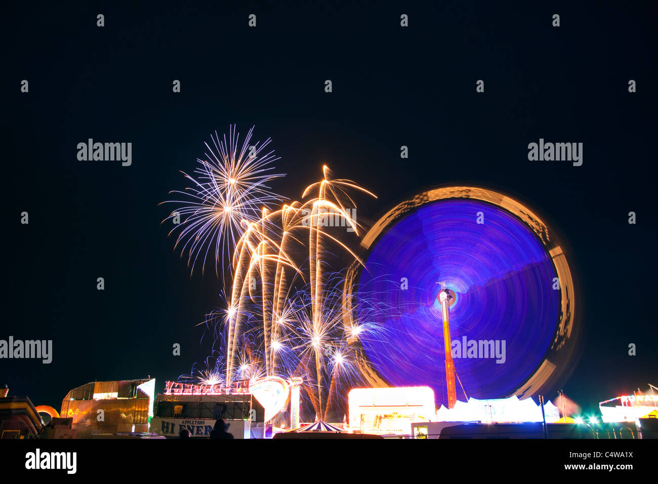 Firework display with illuminated Ferris wheel at night during Cromer ...