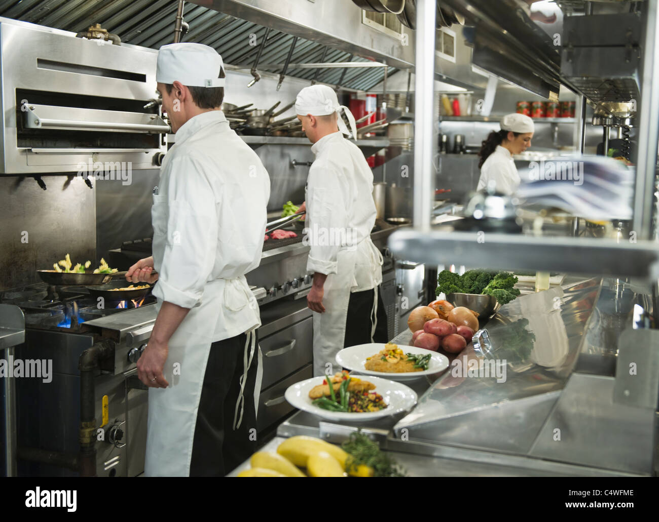 USA, New York State, New York City, Chefs preparing food in kitchen ...