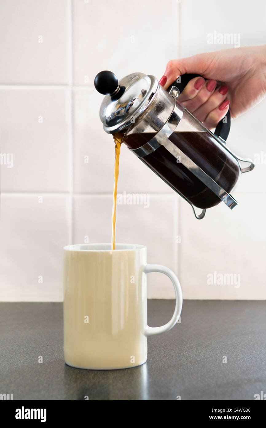 Young Caucasian womans hand pouring coffee into mug from cafetiere ...