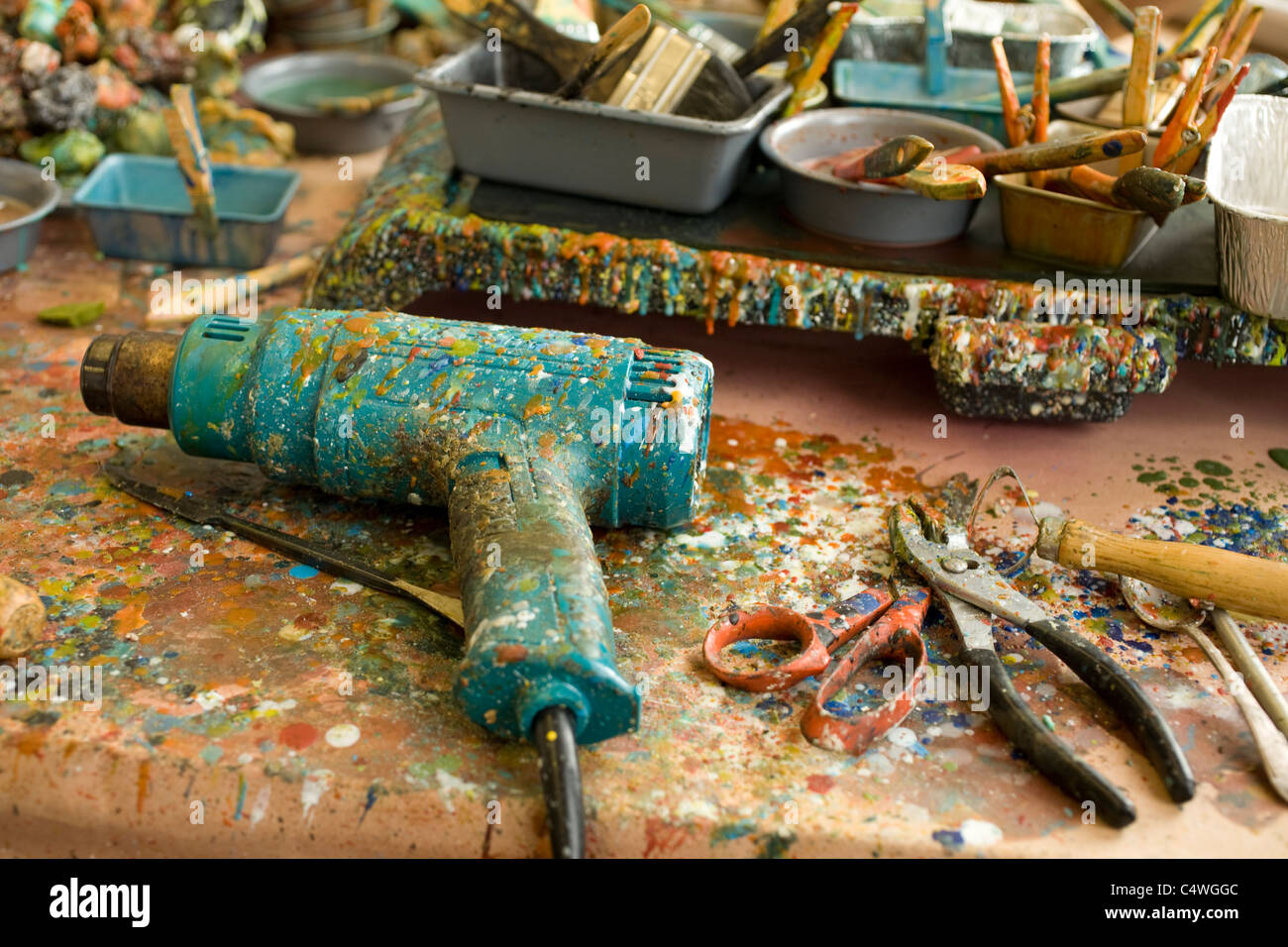 Encaustic artist has tools on her bench, covered with dripped colored ...