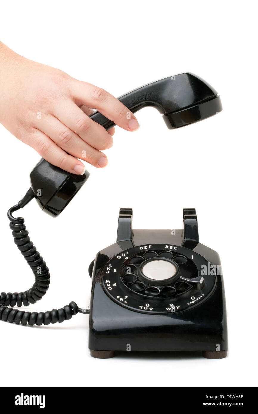 A hand holding the handset of an old black vintage rotary style ...