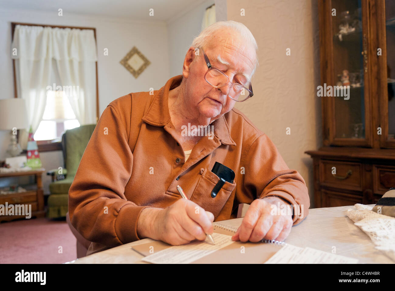 A retired elderly Senior Man signing papers in his home Stock Photo - Alamy