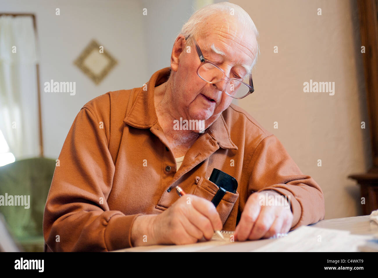 A retired elderly Senior Man signing papers in his home Stock Photo - Alamy