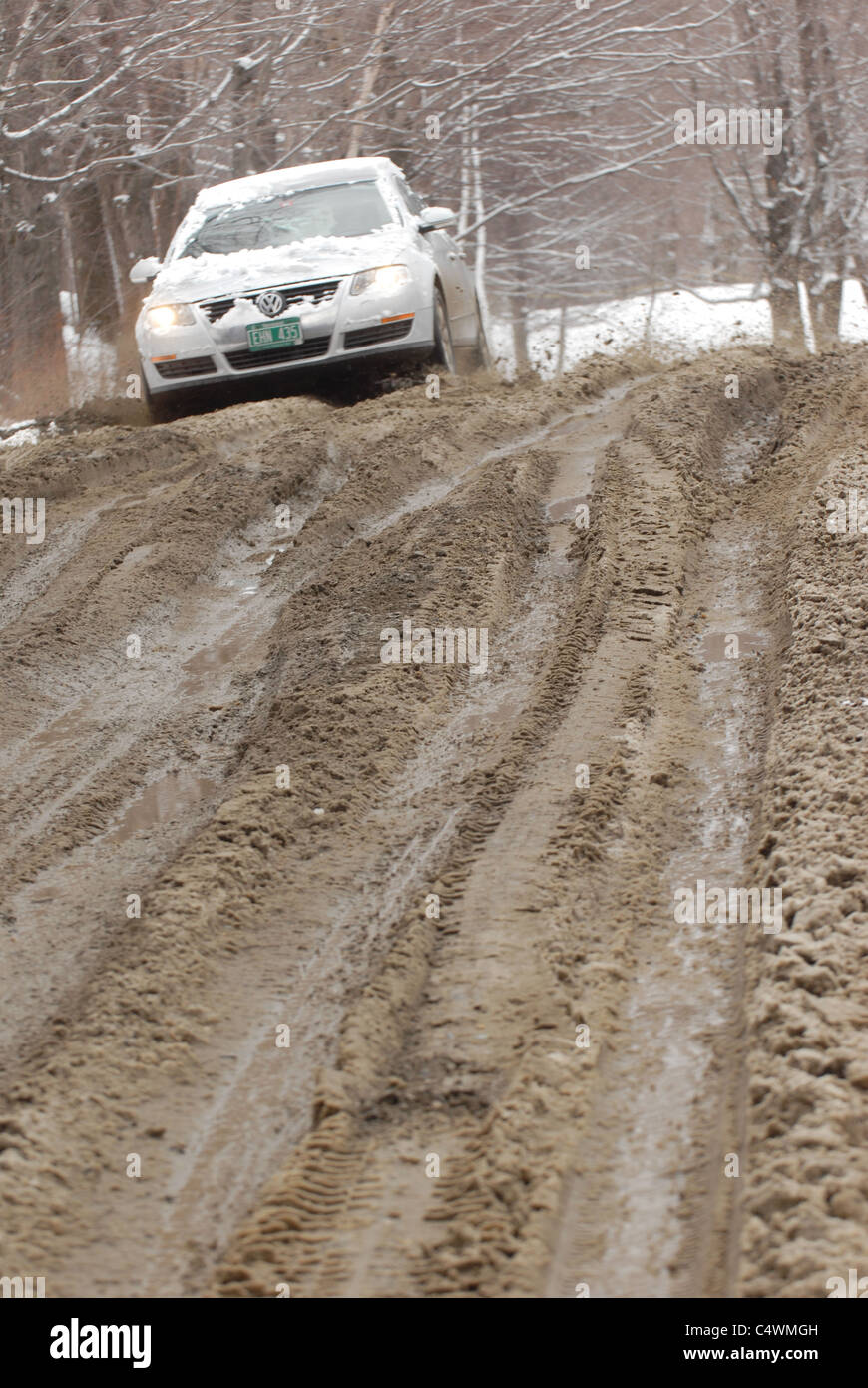 A car makes it’s way along a muddy road during mud season in Vermont in ...