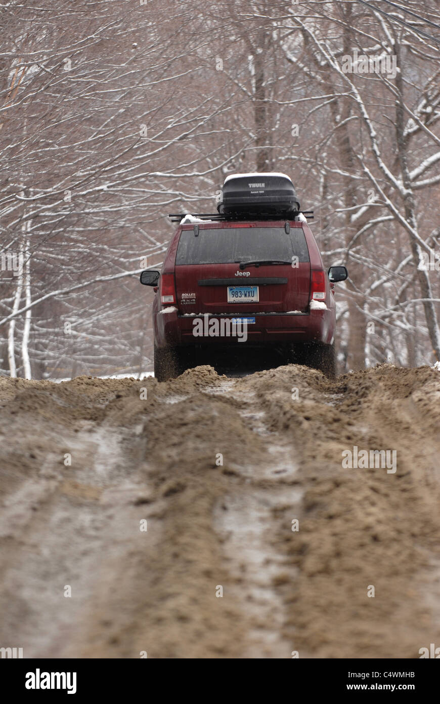 A car makes it’s way along a muddy road during mud season in Vermont in ...