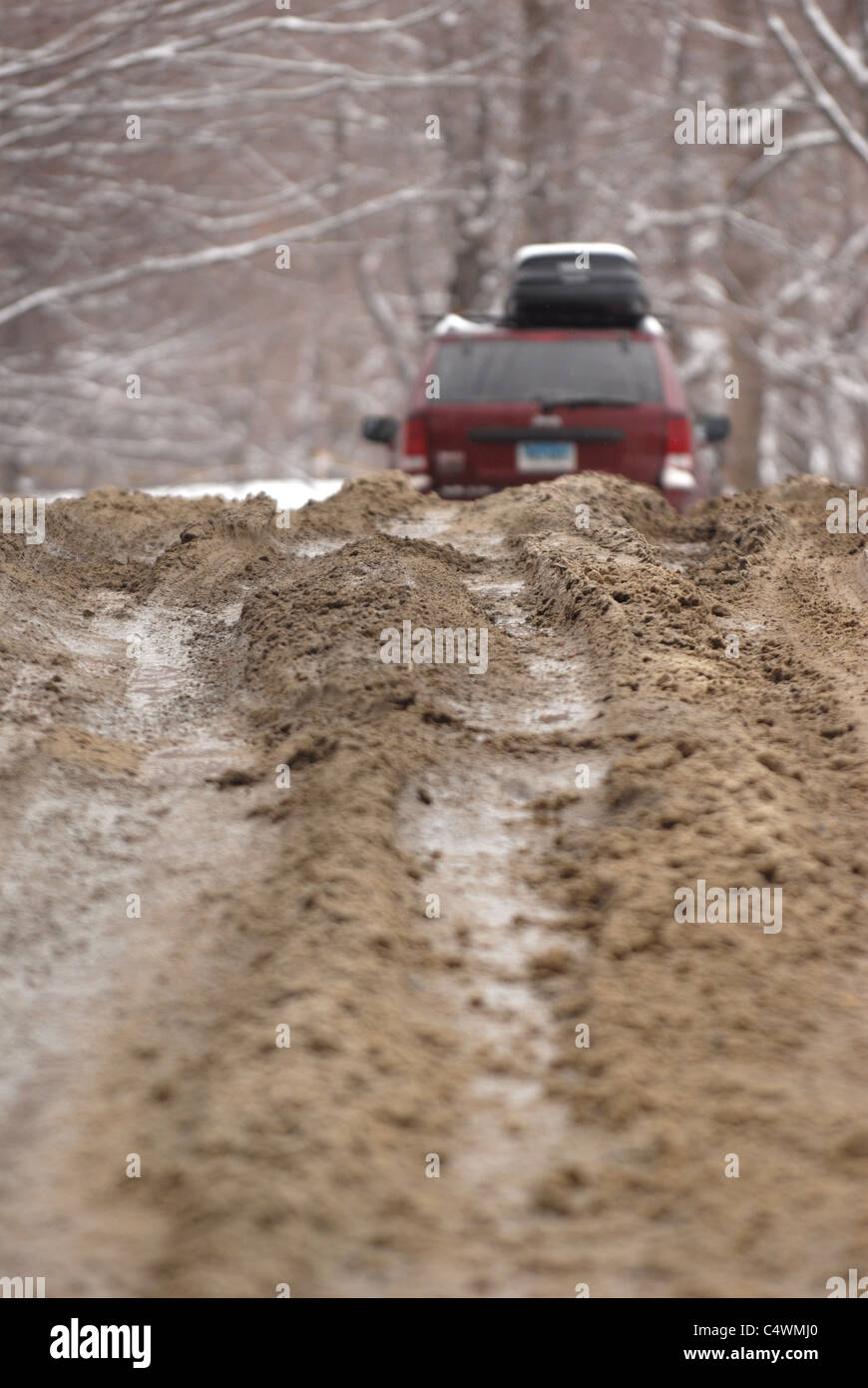 A car makes it’s way along a muddy road during mud season in Vermont in ...