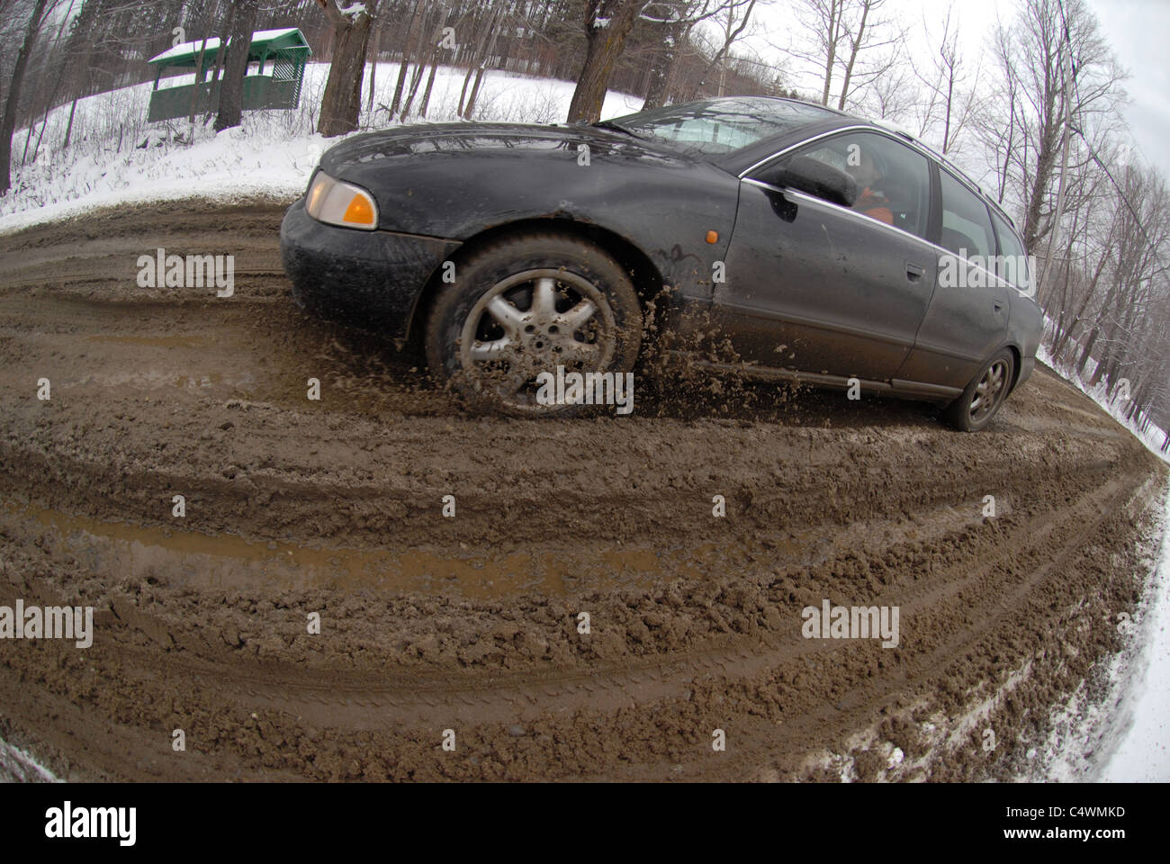 A car makes it’s way along a muddy road during mud season in Vermont in ...