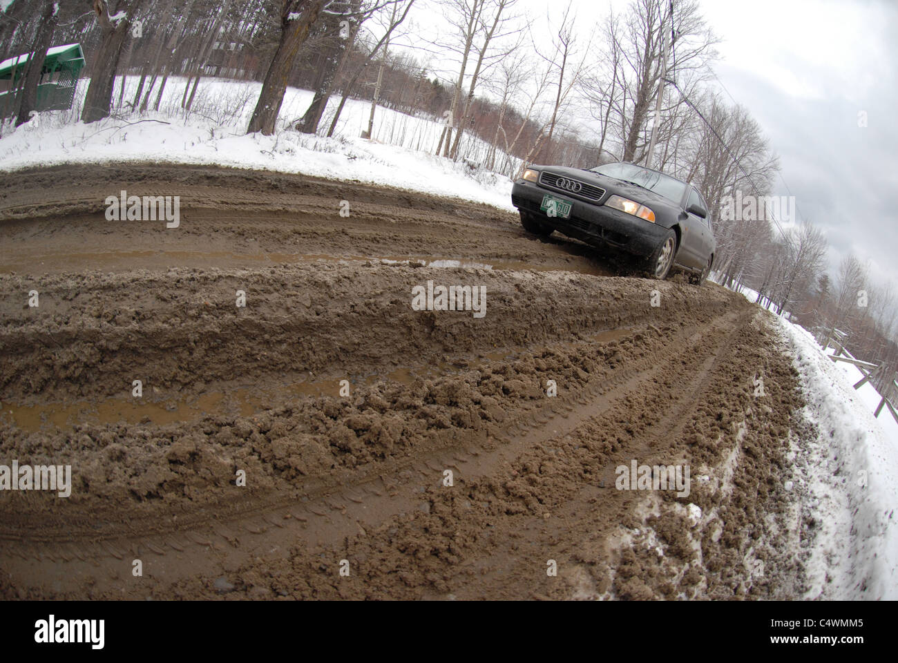A car makes it’s way along a muddy road during mud season in Vermont in ...