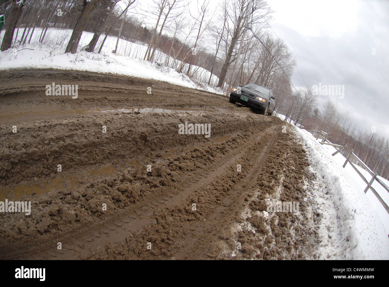 A car makes it’s way along a muddy road during mud season in Vermont in ...