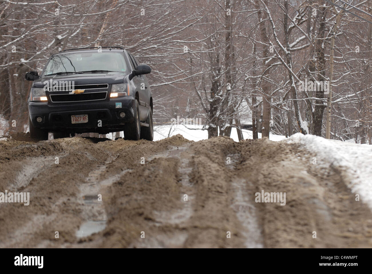 A car makes it’s way along a muddy road during mud season in Vermont in ...