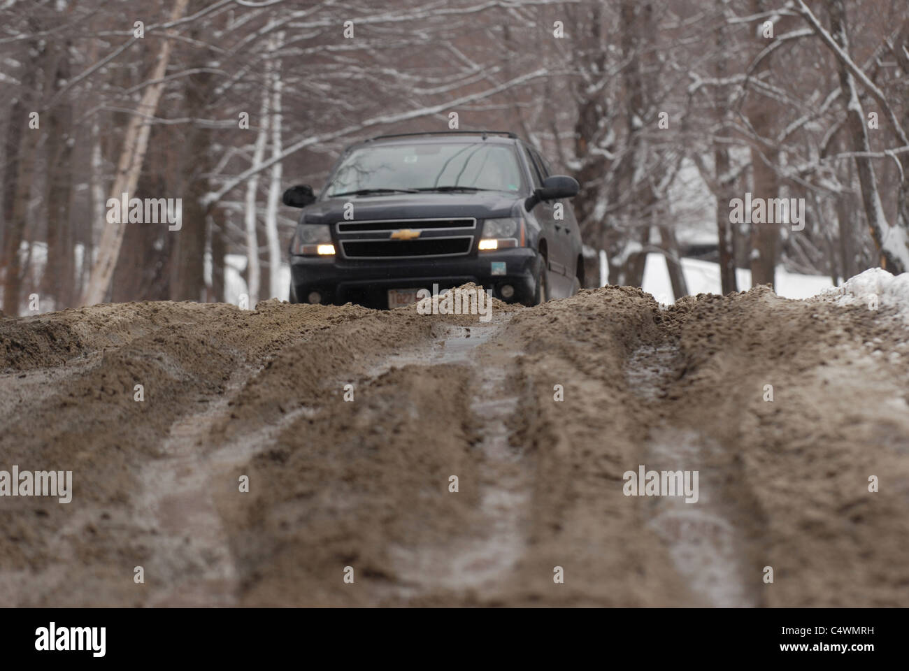 A car makes it’s way along a muddy road during mud season in Vermont in ...