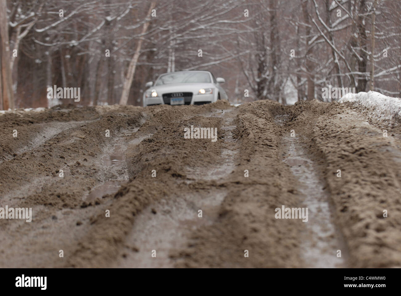 A car makes it’s way along a muddy road during mud season in Vermont in ...
