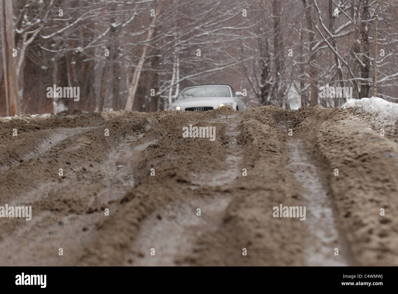 A car makes it’s way along a muddy road during mud season in Vermont in ...