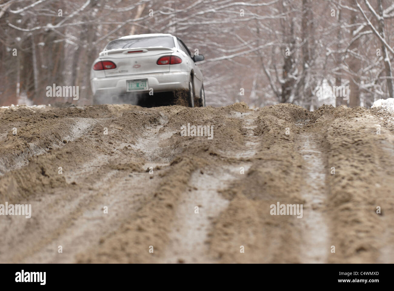A car makes it’s way along a muddy road during mud season in Vermont in ...