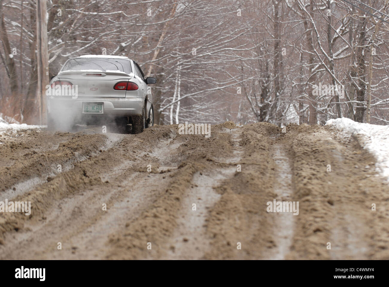 A car makes it’s way along a muddy road during mud season in Vermont in ...