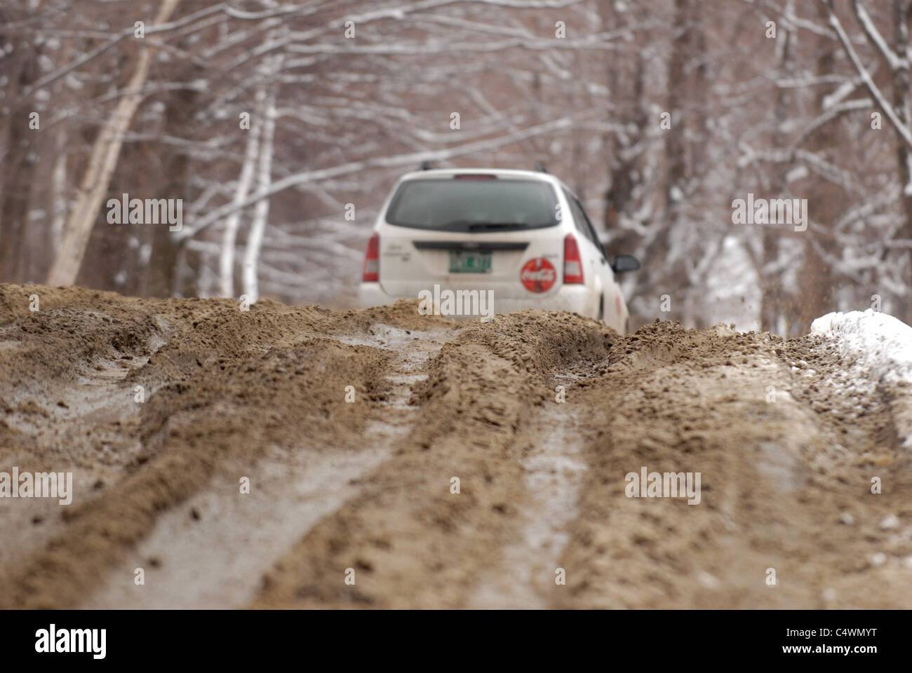A car makes it’s way along a muddy road during mud season in Vermont in ...