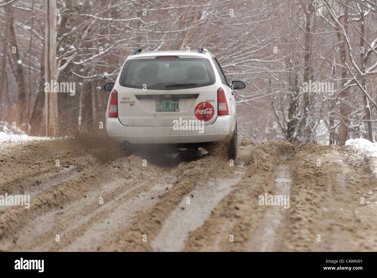 A car makes it’s way along a muddy road during mud season in Vermont in ...