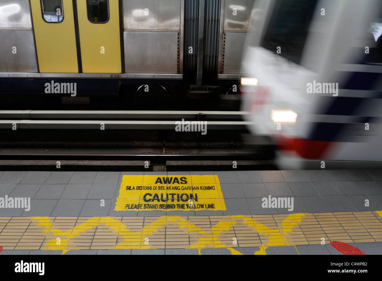 Stand behind the yellow line caution at a train platform in Kuala ...