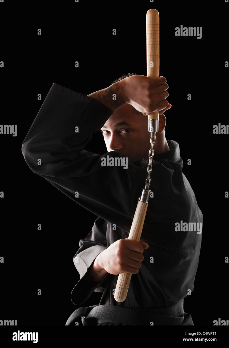 Studio shot of man exercising with nunchaku Stock Photo - Alamy