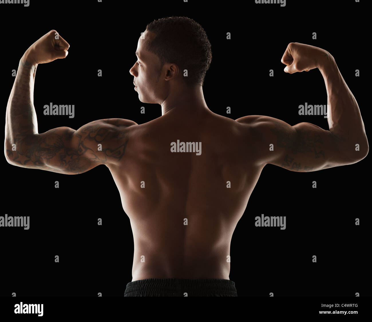 Rear view of muscular man flexing muscles Stock Photo - Alamy