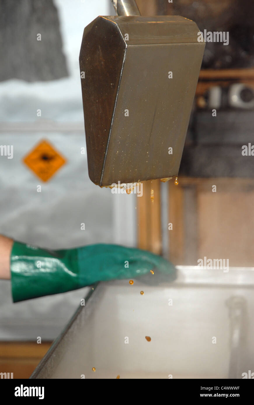Maple syrup drips from a ladle in the process of boiling maple sap into ...