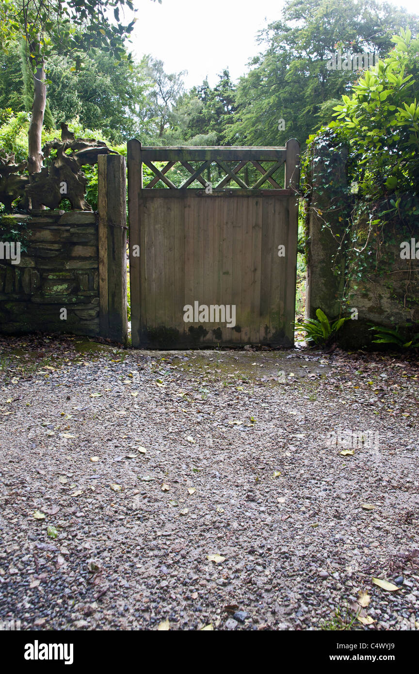 A stout wooden gate set into a stone wall. The foreground is crushed ...