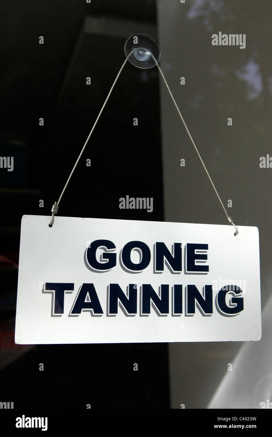 A Gone Tanning sign hangs in a shop window Stock Photo - Alamy
