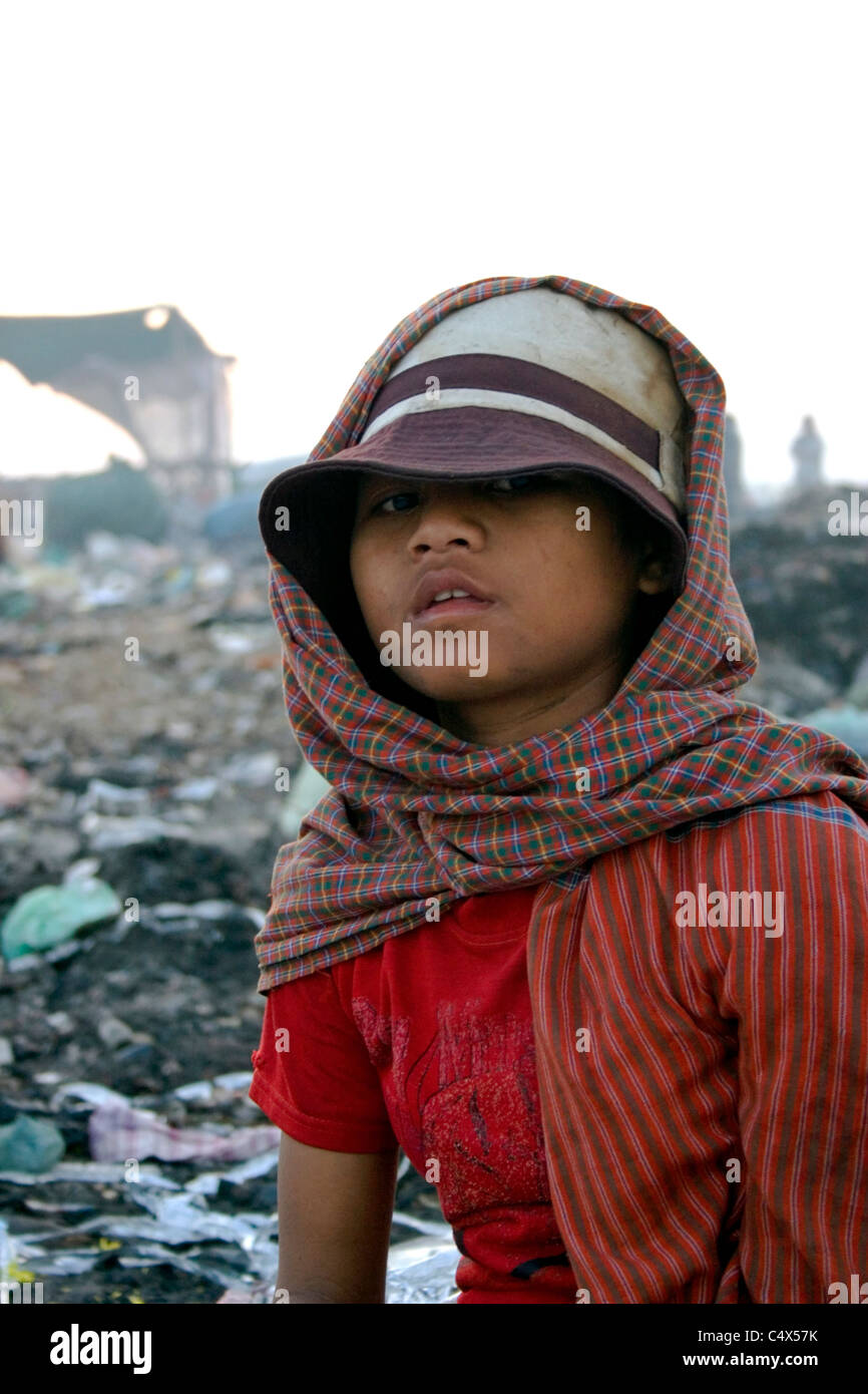 A young child laborer girl is searching through shredded plastic at a ...