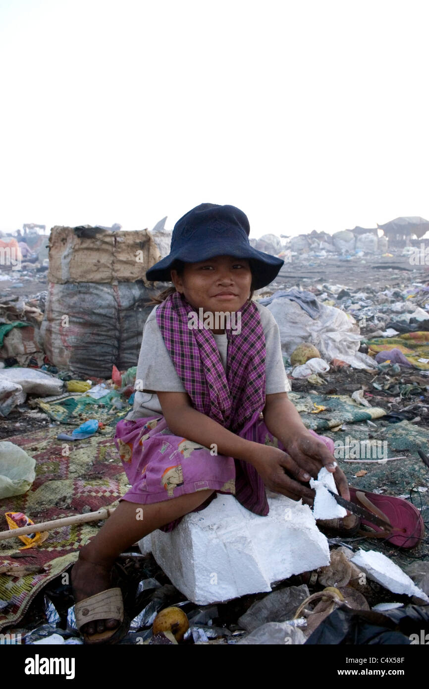A young child laborer girl is searching through garbage at a polluted ...