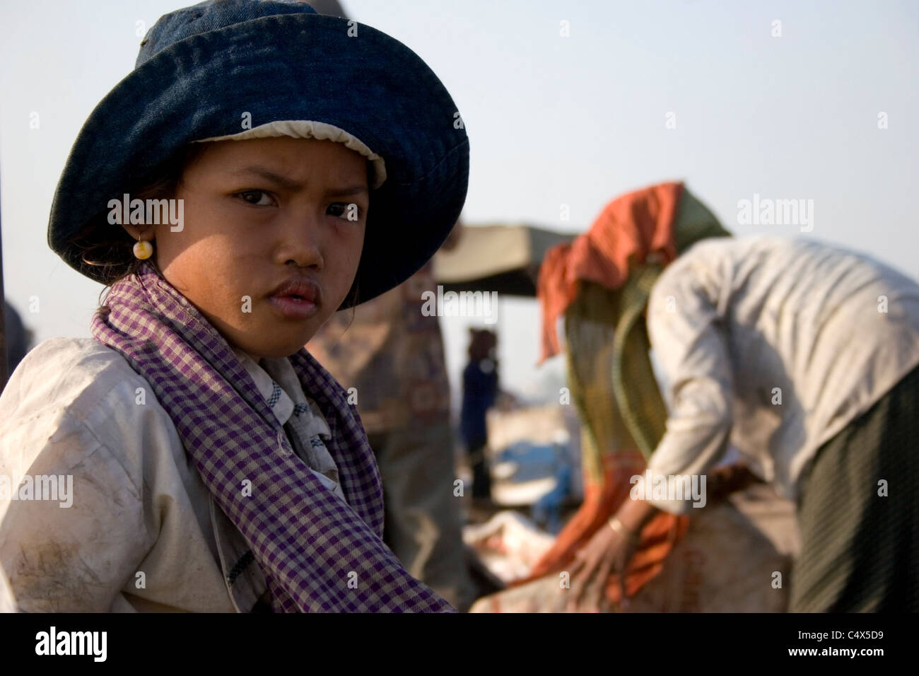 A young child laborer girl wearing a hat is working at a toxic and ...