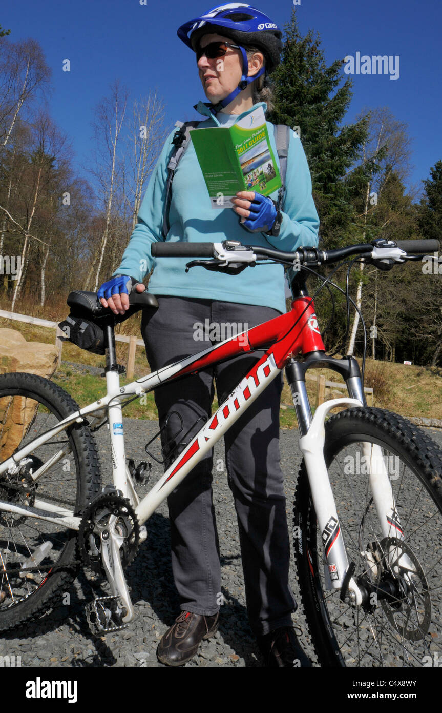 Female cyclist choosing a cycle route in Kielder Water & Forest Park ...