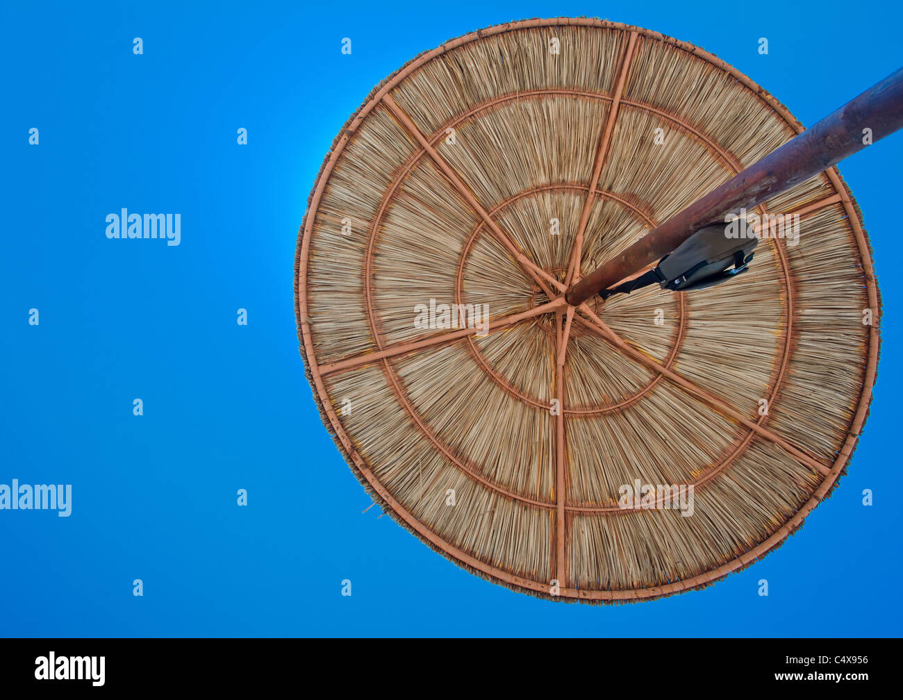 Straw beach parasol photographed from below against the blue sky ...