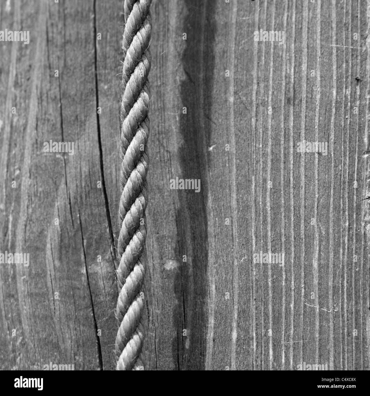 A rope hanging outside casts a shadow on a piece of wood Stock Photo ...