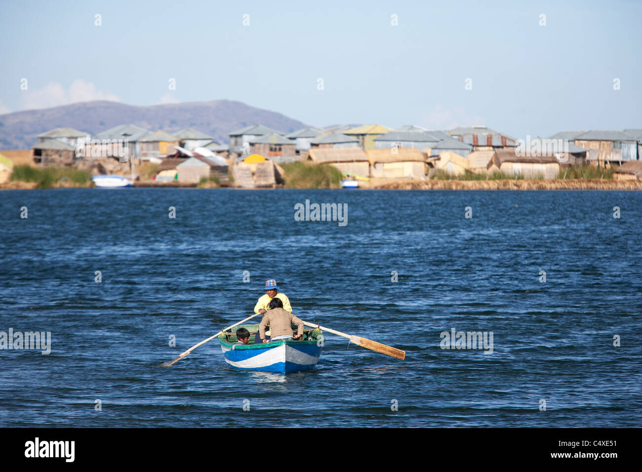 A rowing boat with two people rowing across the Uros islands on Lake ...