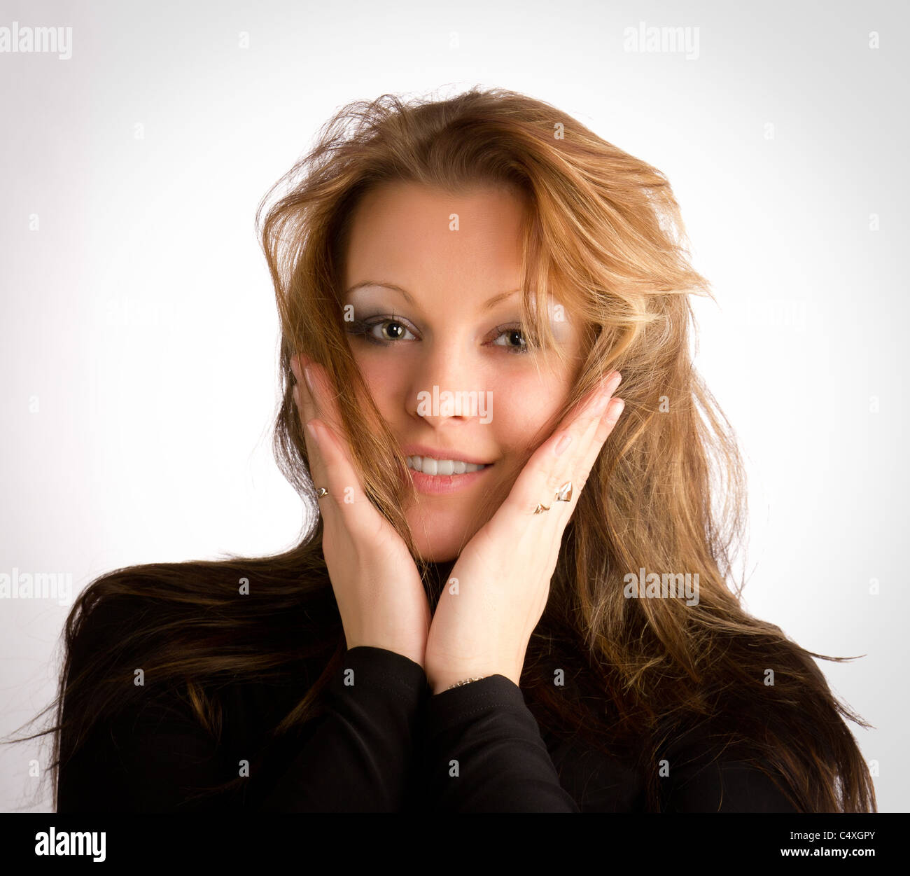 Young beautiful woman with long brown hair holding her checks with both ...