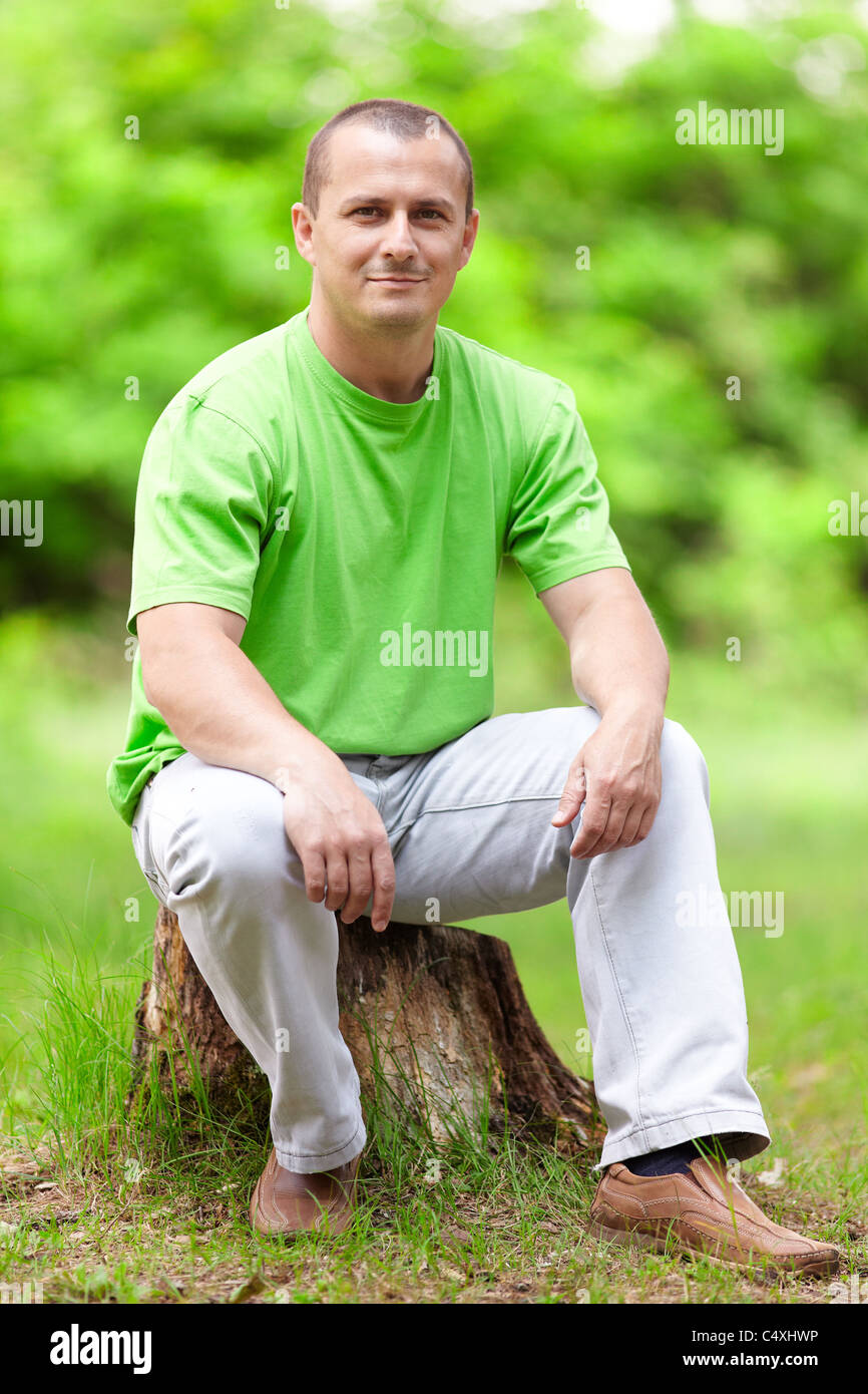 Portrait of a young man sitting on a tree stump in the forest Stock ...