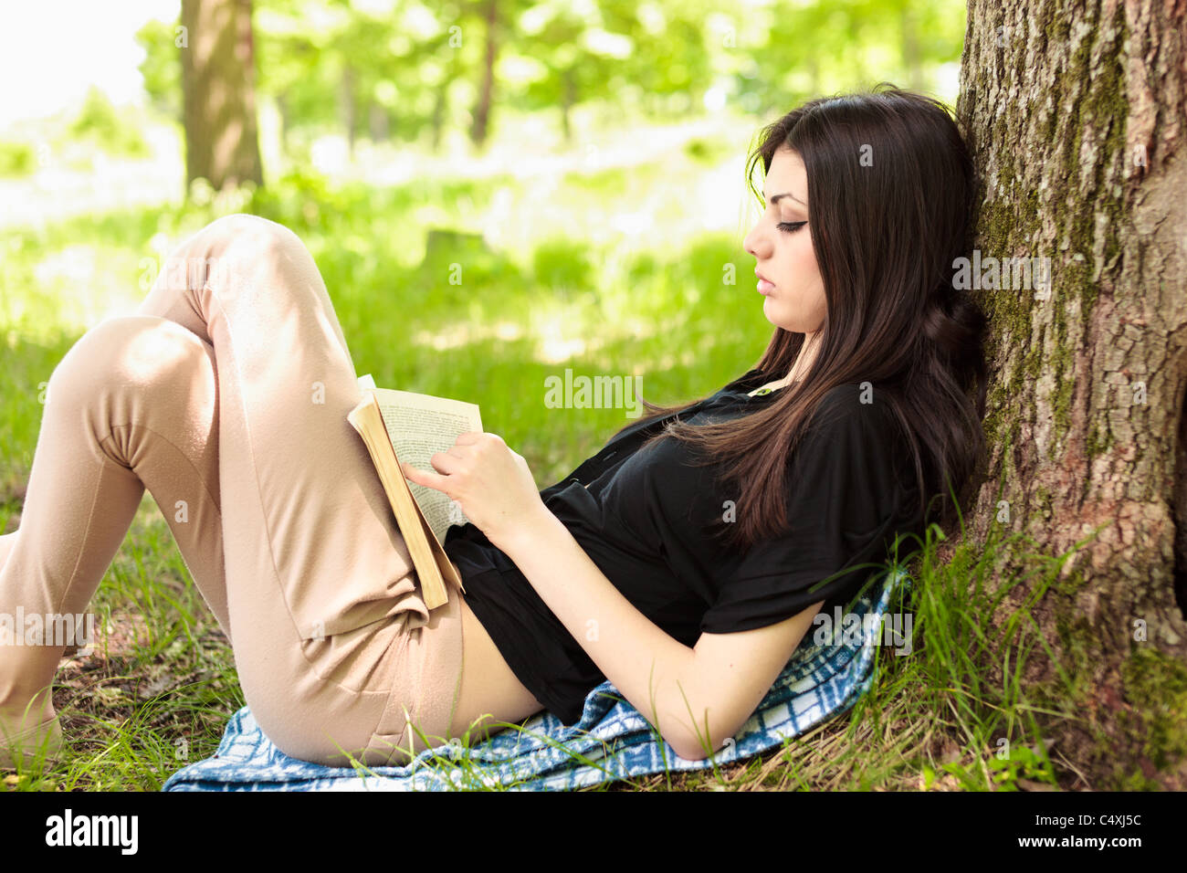 Attractive young woman reading a book outdoor in the forest Stock Photo ...