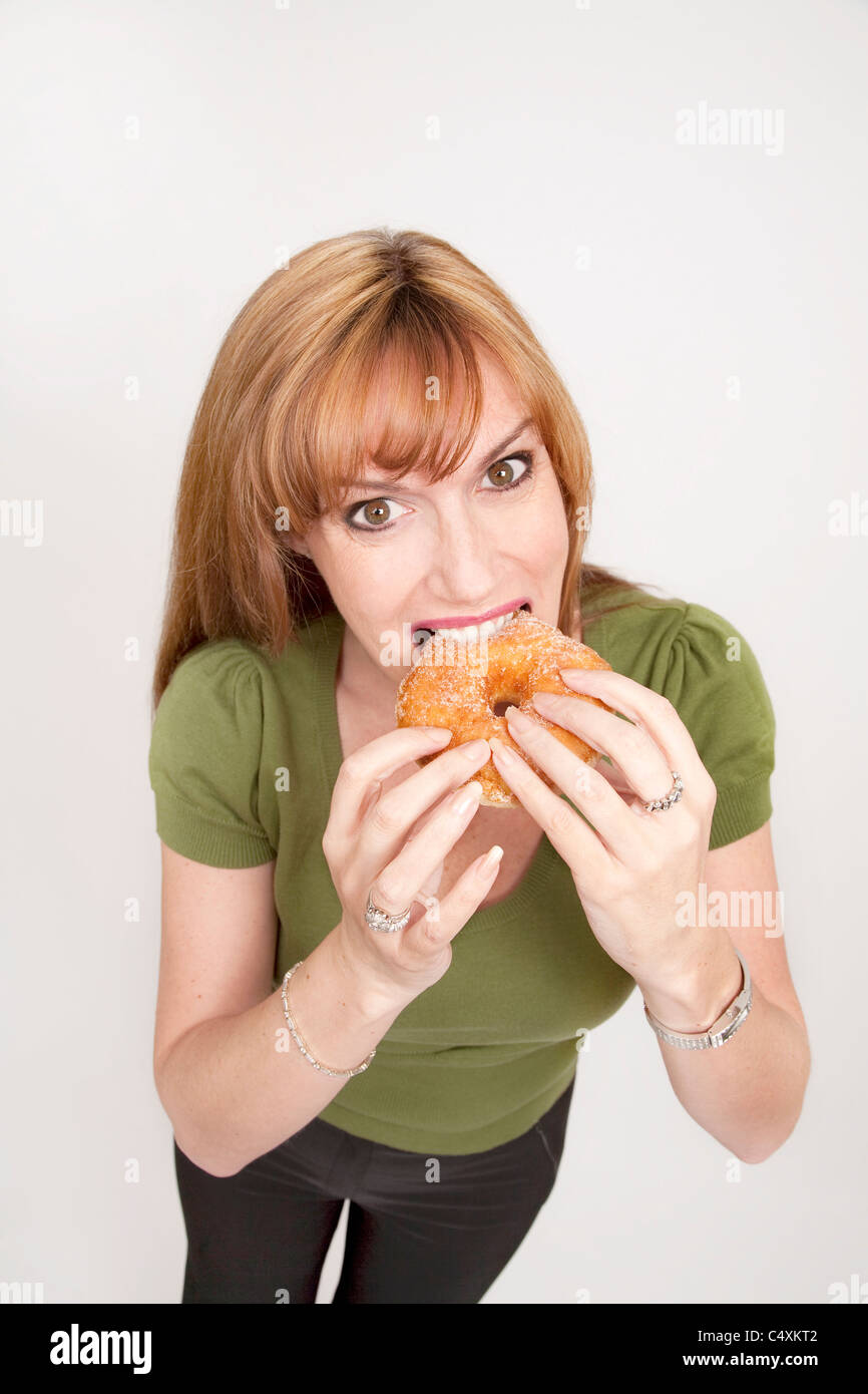 Woman taking a bite of a doughnut Stock Photo - Alamy