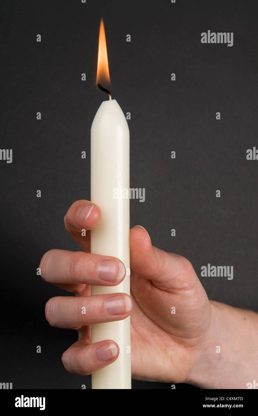 Woman's hand holding a candle, against black background Stock Photo - Alamy
