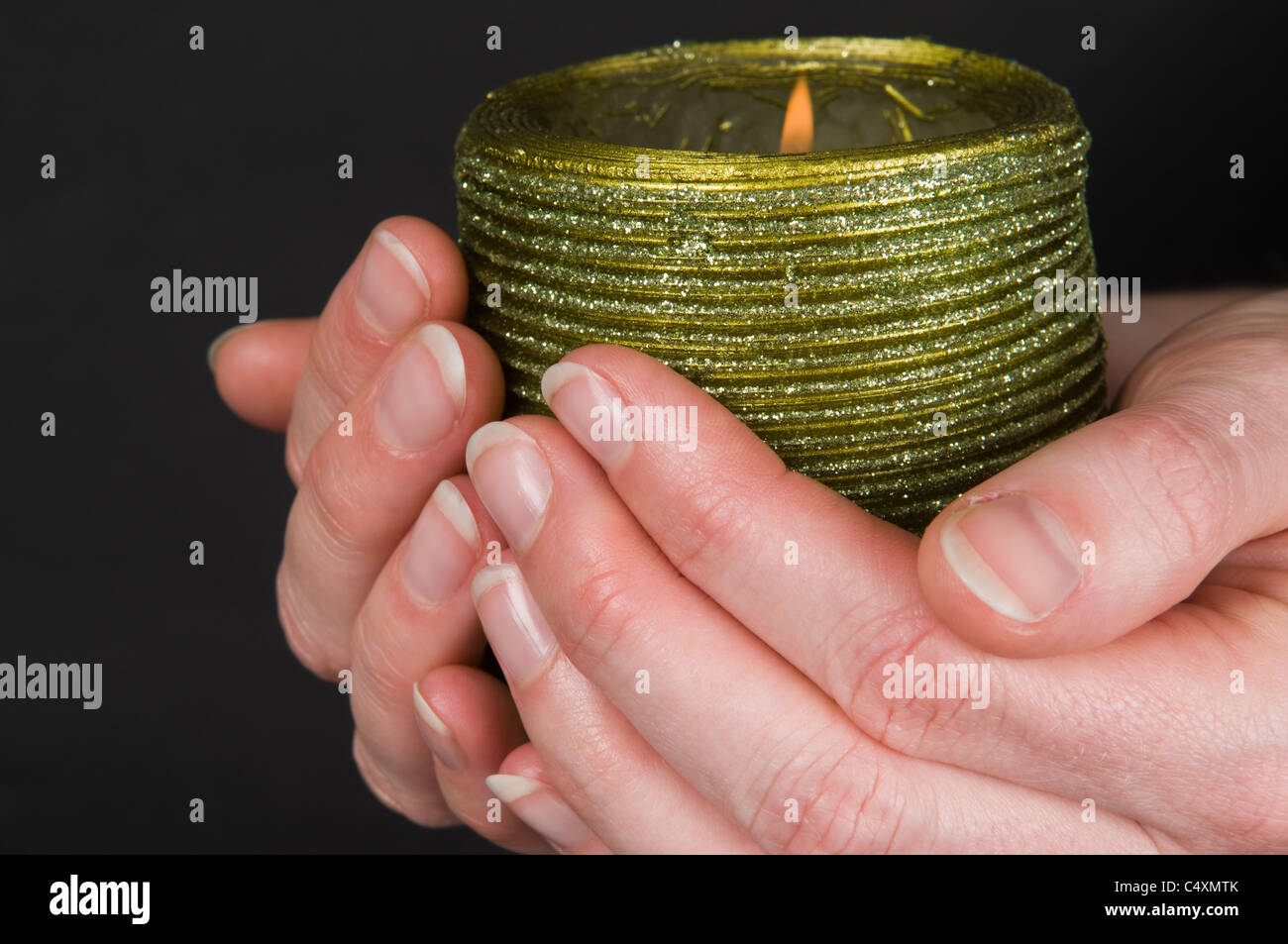 Woman's hand holding a candle, against black background Stock Photo - Alamy