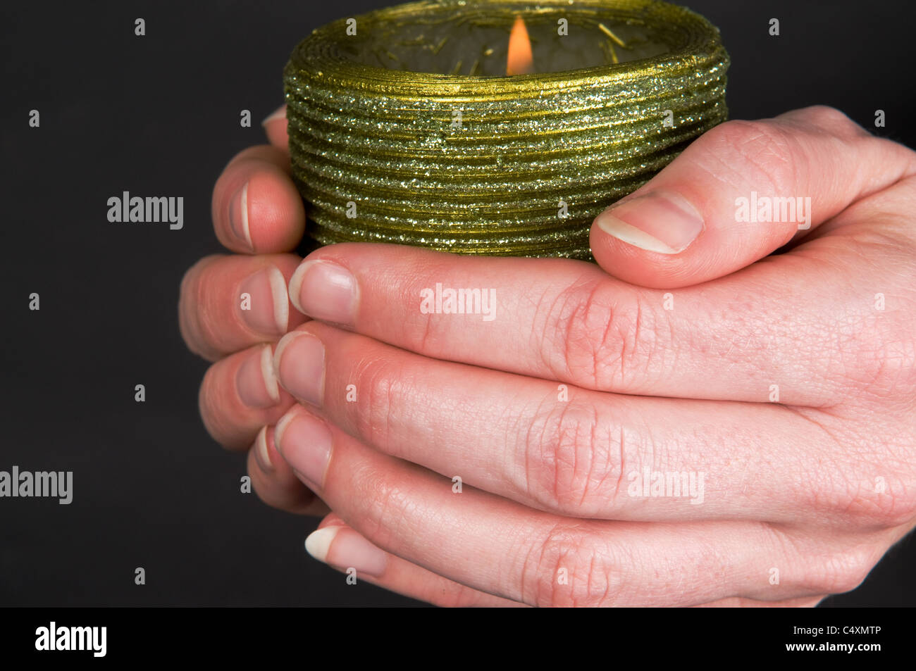 Woman's hand holding a candle, against black background Stock Photo - Alamy