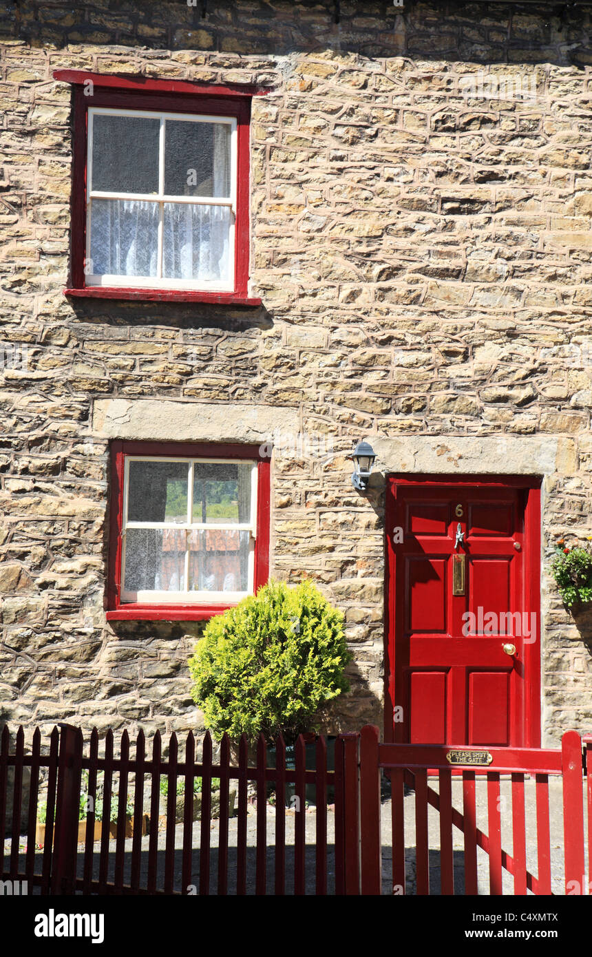 A traditional stone cottage with bright red painted door and windows ...