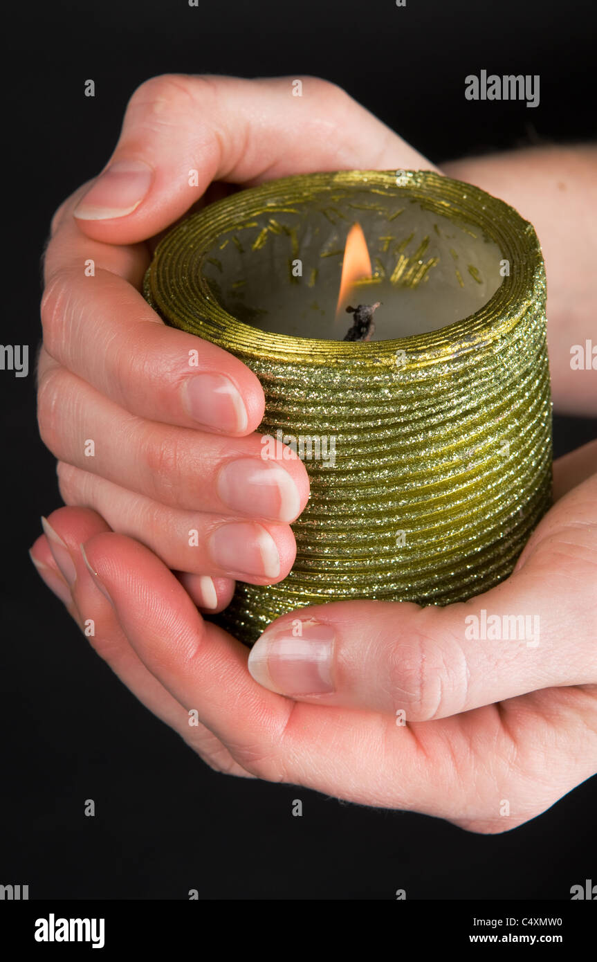 Woman's hand holding a candle, against black background Stock Photo - Alamy
